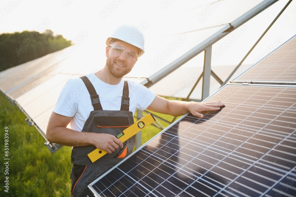 Side view of male worker installing solar modules and support ...