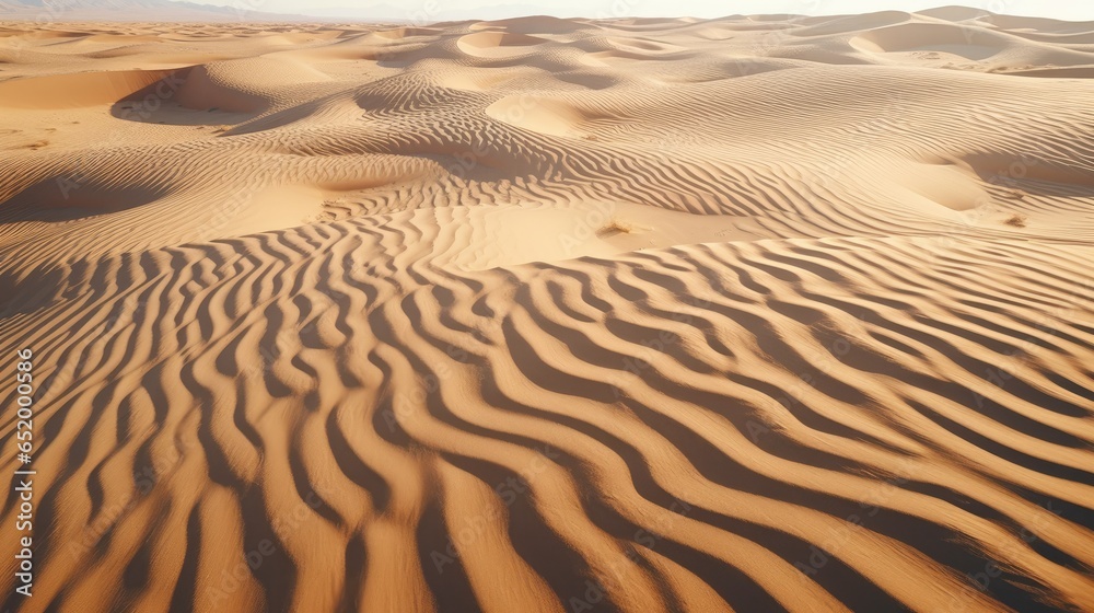A breathtaking aerial view of wind-sculpted sand dunes in an arid desert region. The overhead ...
