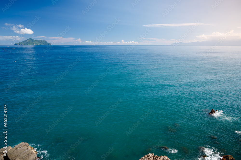 Blue sea and blue sky with changing white clouds. Small islands and ...