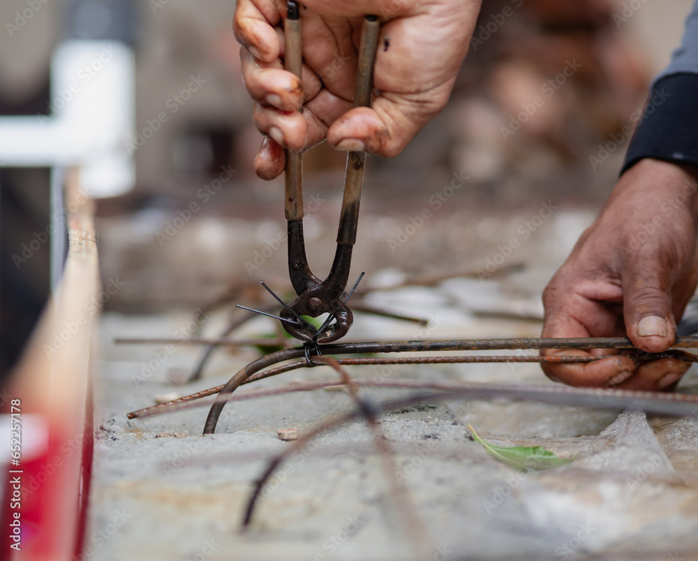Labor constructor ties steel wire to secure bars rod for reinforcement ...