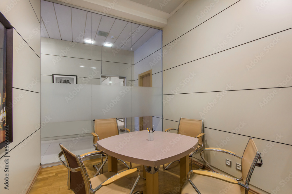 A small meeting room in the office with a glass wall and furniture in ...