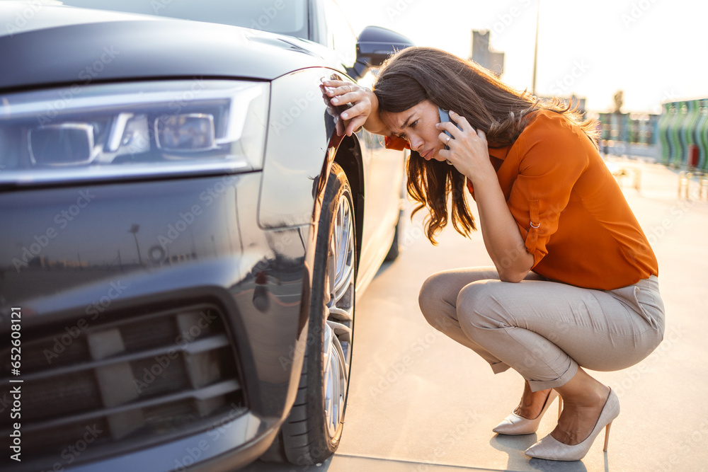 Sad woman sits at the punctured wheel of a car. Tire service and car ...