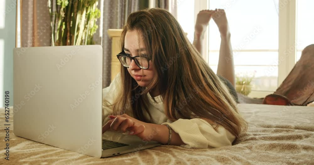 Young girl in glasses typing and working on the laptop computer as ...