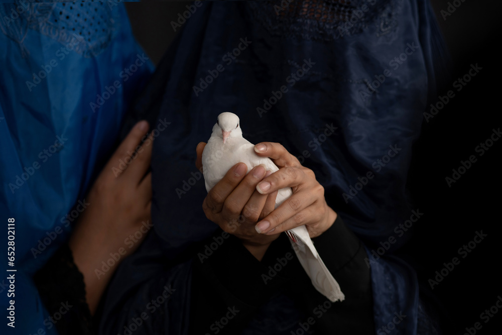 Two Muslim women in traditional burqa hold white doves in their hands ...