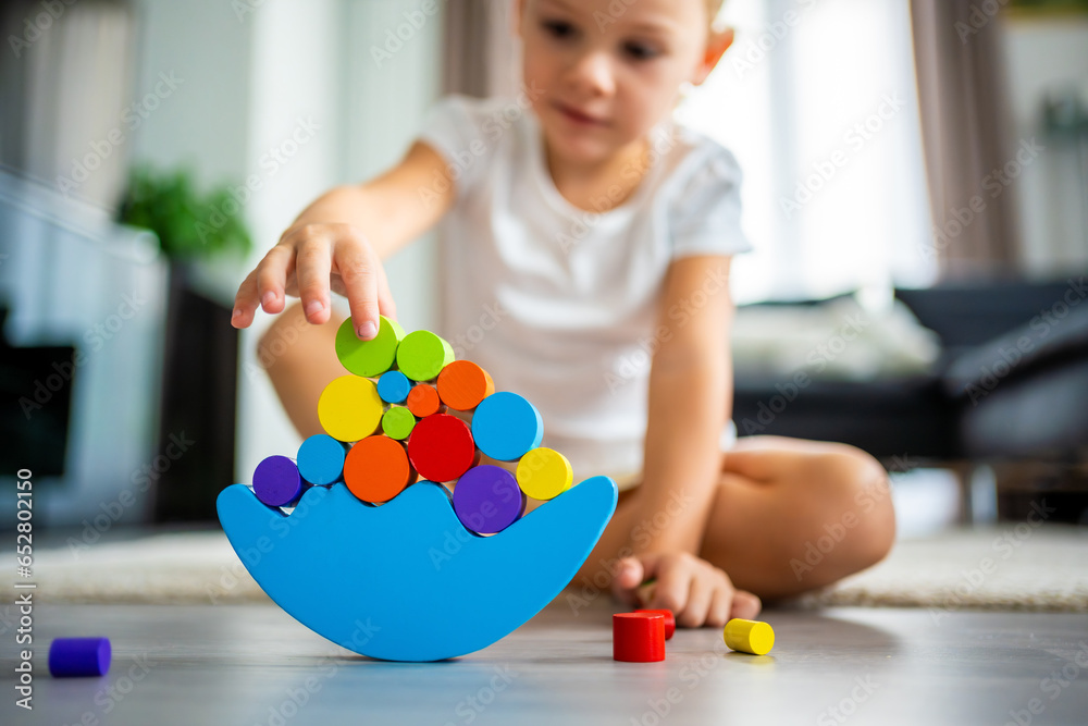 Little girl playing with wooden balancing toy on the floor in home ...