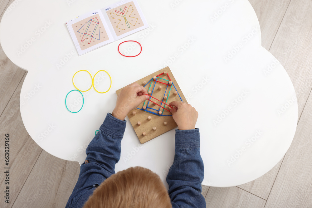 Motor skills development. Boy playing with geoboard and rubber bands at ...