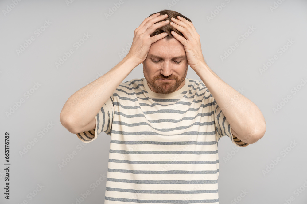 Extremely disappointed man holds head. Young guy, isolated on gray ...