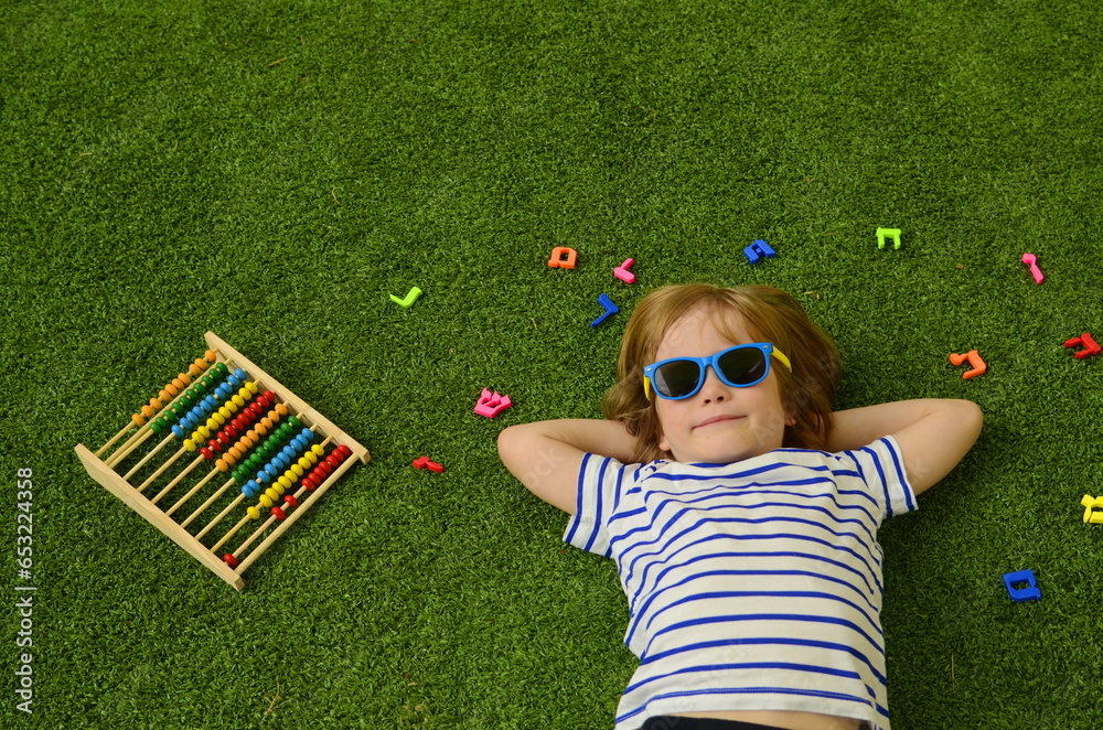 Hebrew alphabet. The boy lies on the grass, letters lie around his head ...
