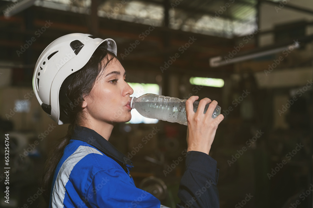 Female factory worker drinking water in break time in factory. Woman ...