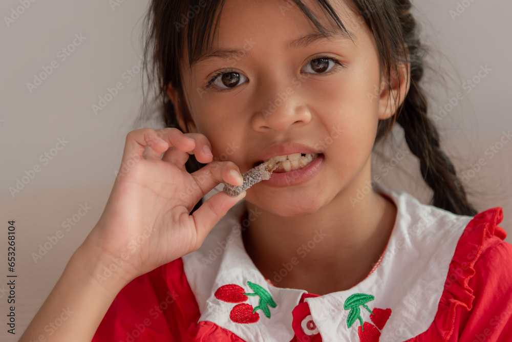A cute asian girl braid hair, red dress eating delicious sugary jelly ...