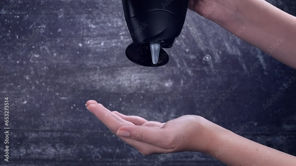 Cleansing body wash in black bottle poured into woman palm. Skin ...