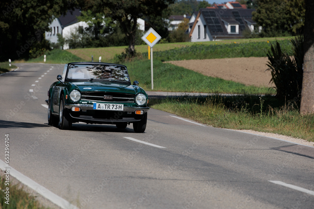 Green Triumph TR6 from the 70's driving on a country road near ...