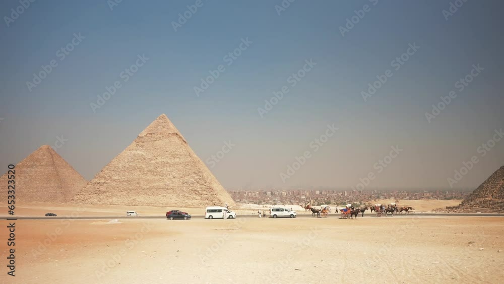 Panoramic view of The Pyramids of Giza and cars and buses with tourists ...