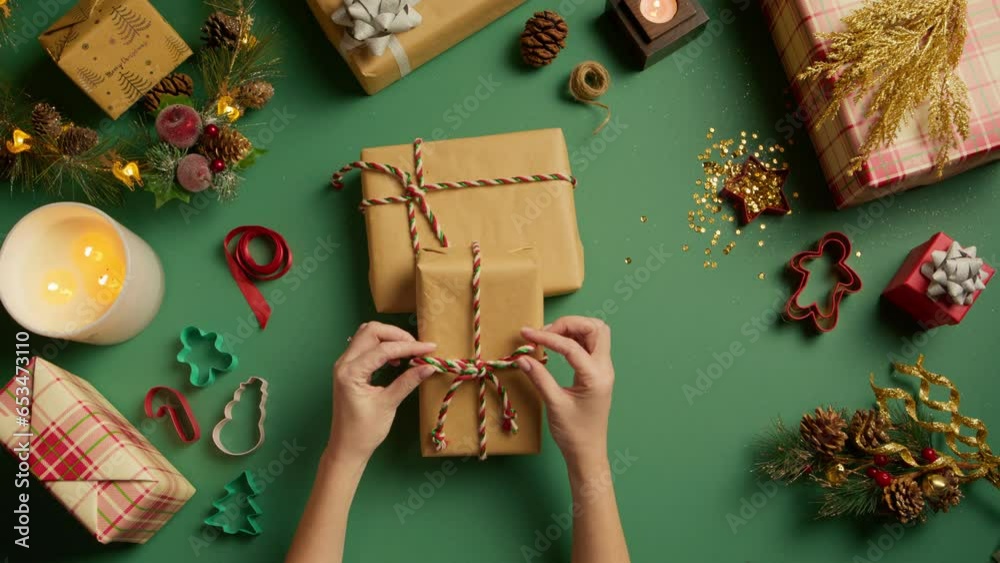 Female hands put and finalize Christmas gift wrapped in craft paper on ...