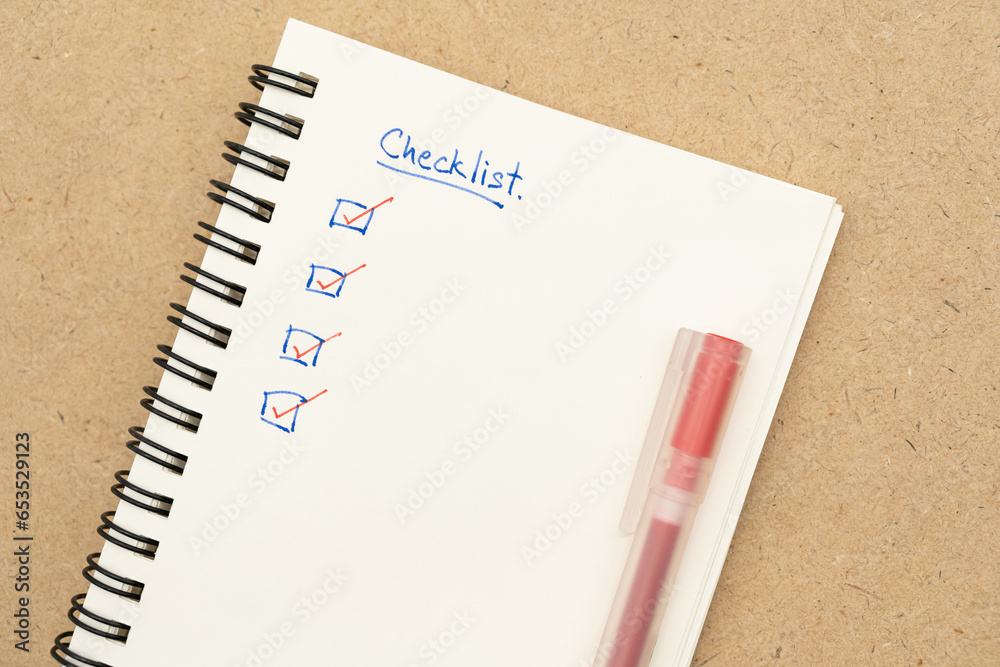 Top view of notebook with handwritten Checklist text and red pen ...