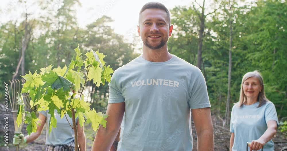 Portrait of handsome cheerful Caucasian man holding tree seedlings ...
