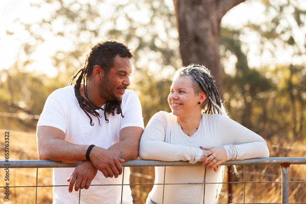 Happy aboriginal Australian couple leaning on farm gate together in ...