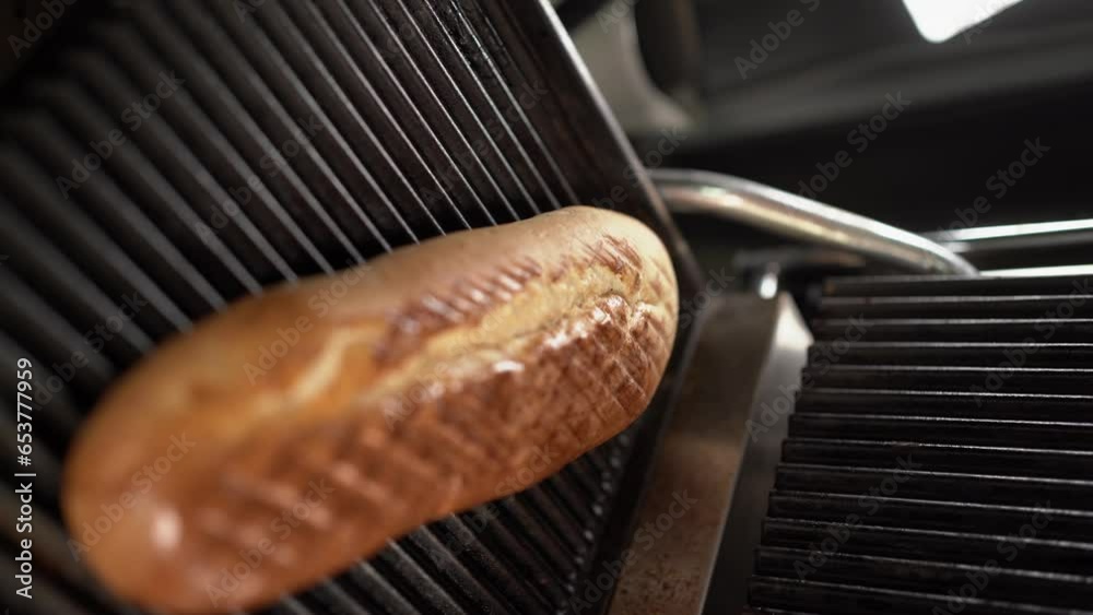 Close-up shot of hot dog bun laying on grate of an electric grill ...