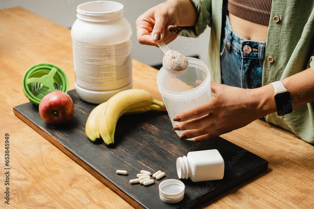Woman in jeans and shirt with a measuring spoon in her hand puts ...