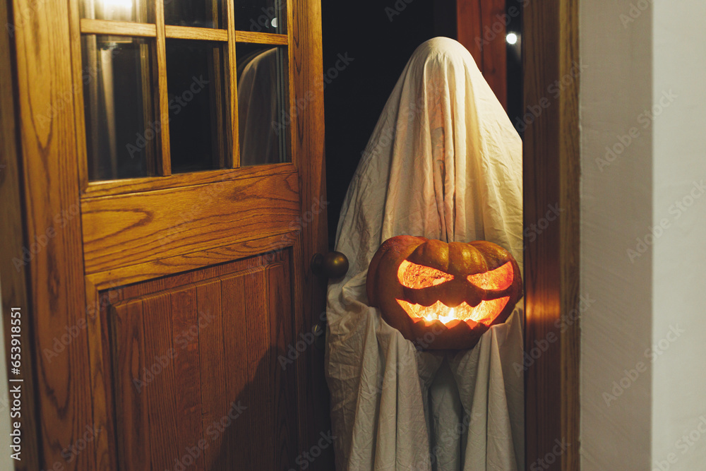 Trick or treat! Spooky ghost holding glowing Jack o lantern pumpkin in ...
