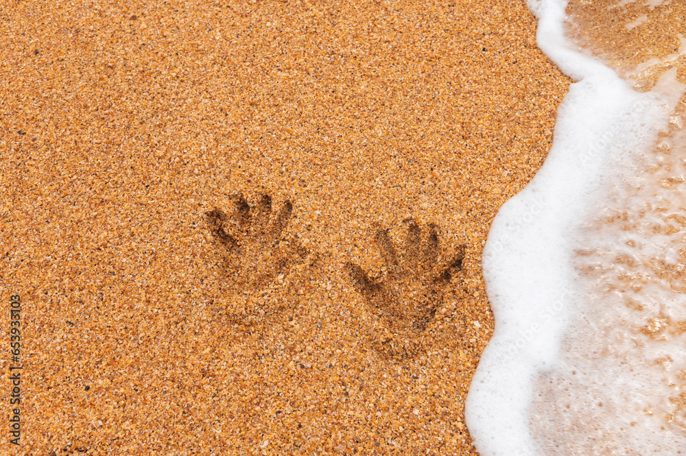 human traces of two hand prints on a sandy beach without people, sea ...