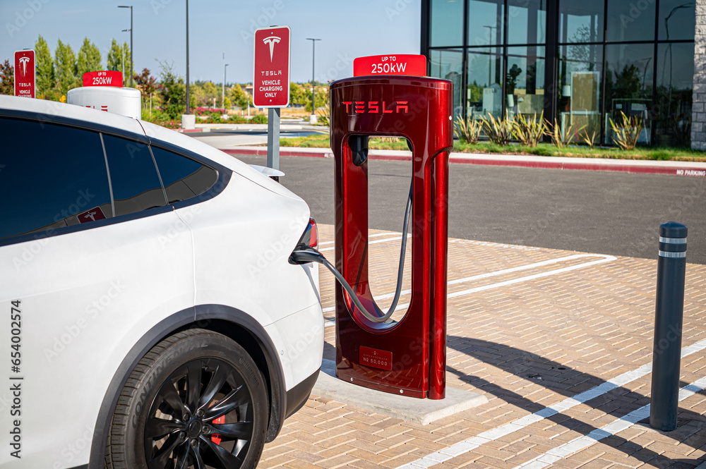A white Model X Tesla charges at the new special crimson edition of the ...