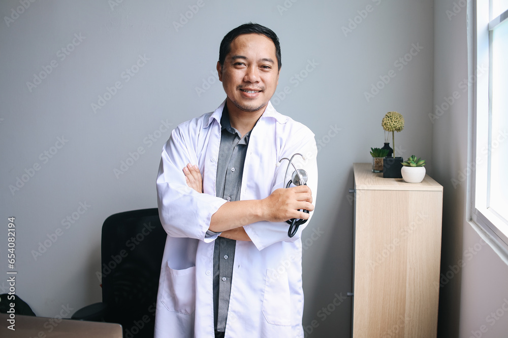 Portrait of friendly young Asian doctor standing folded arms and ...
