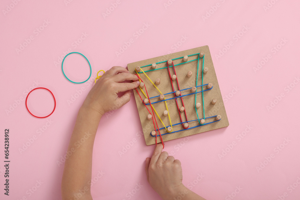 Motor skills development. Boy playing with geoboard and rubber bands at ...