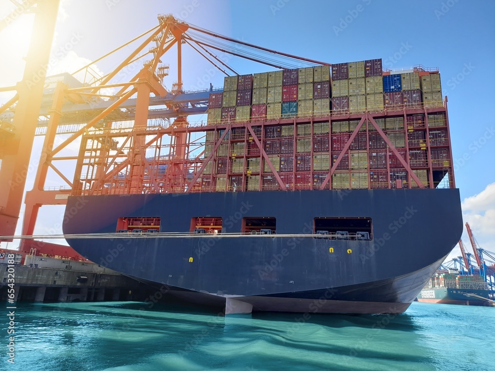 Ein großes Containerschiff legt im Hafen an. Es bringt eine Ladung ...