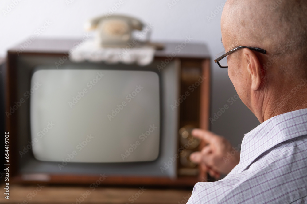 elderly man turns on and watches old retro analog TV with blank screen ...