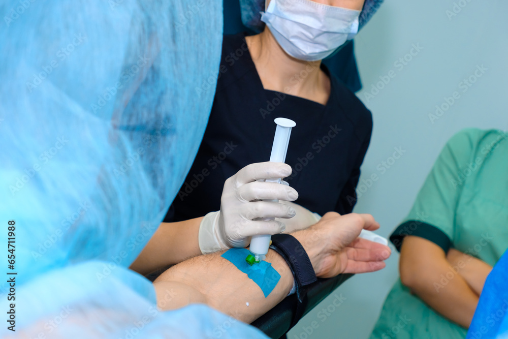 Hands of an anesthesiologist injecting medicine intravenously into the ...