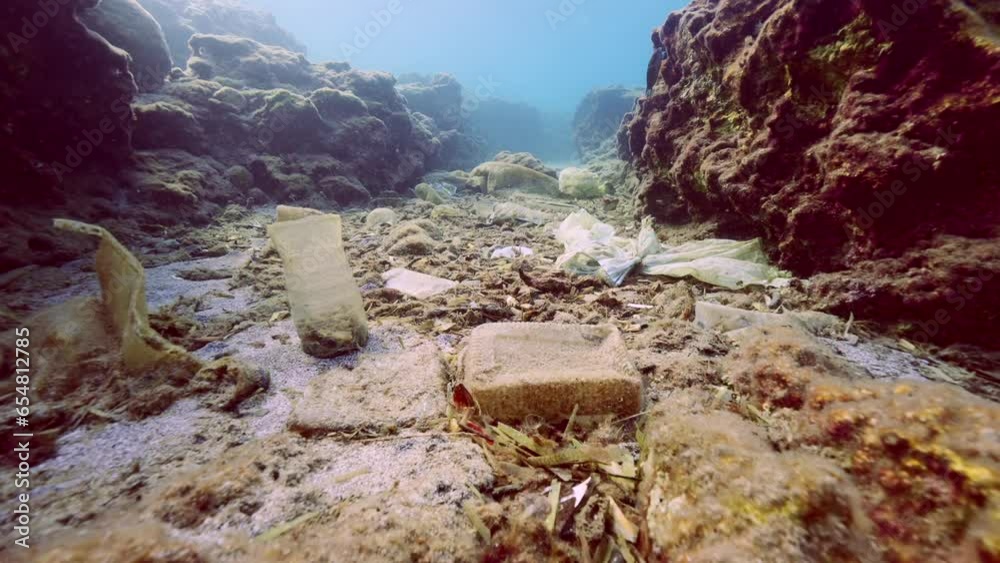 Camera moving forwards between two rocky reefs above seabed polluted ...