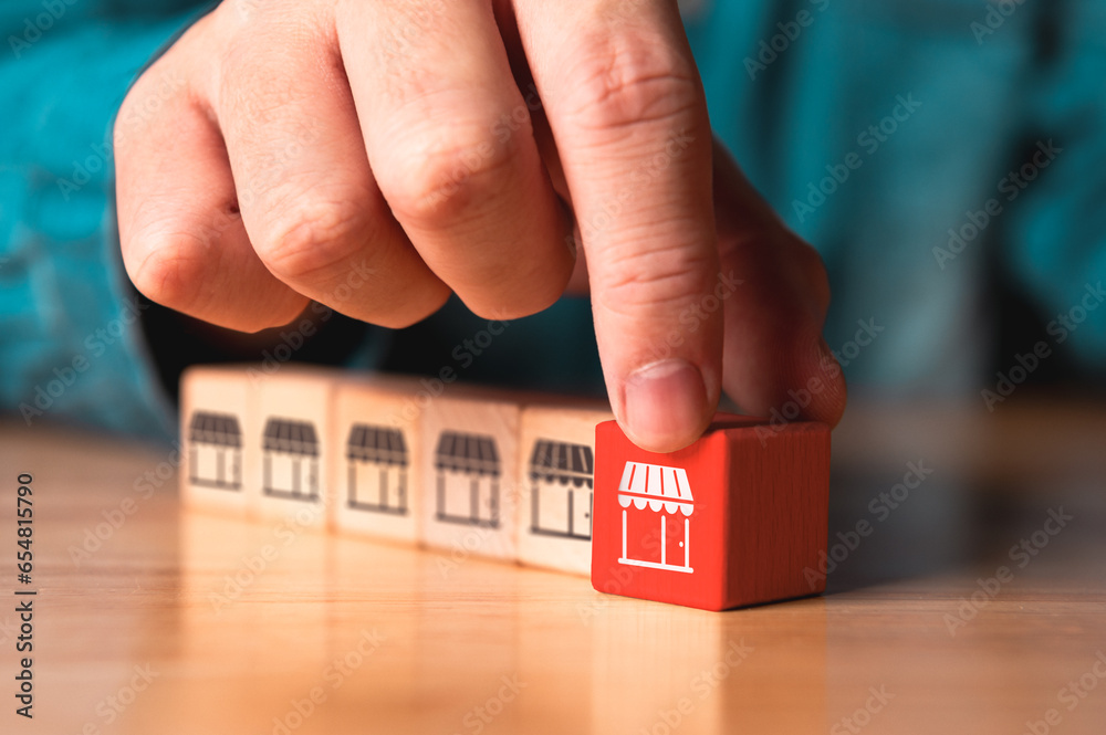 Businessman hand choosing and placing business store franchise wooden ...