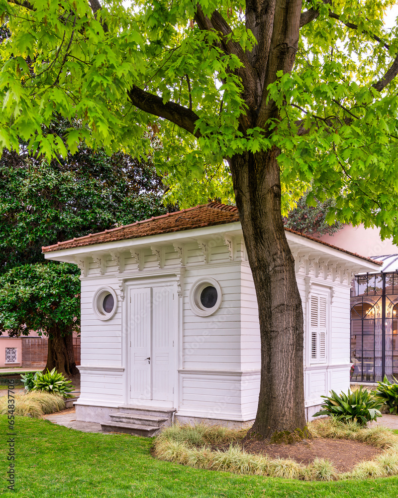 White wooden cottage with closed door and shuttered window sits in a ...