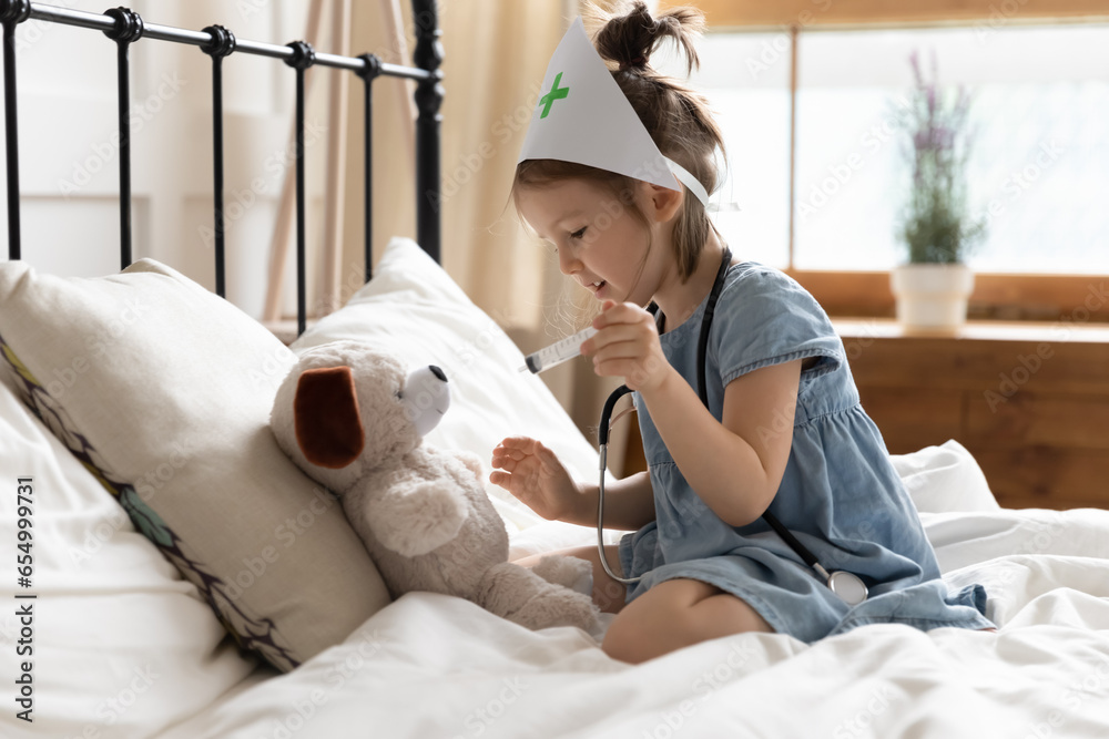 Caring little girl acting as nurse curing favorite fluffy teddy bear ...