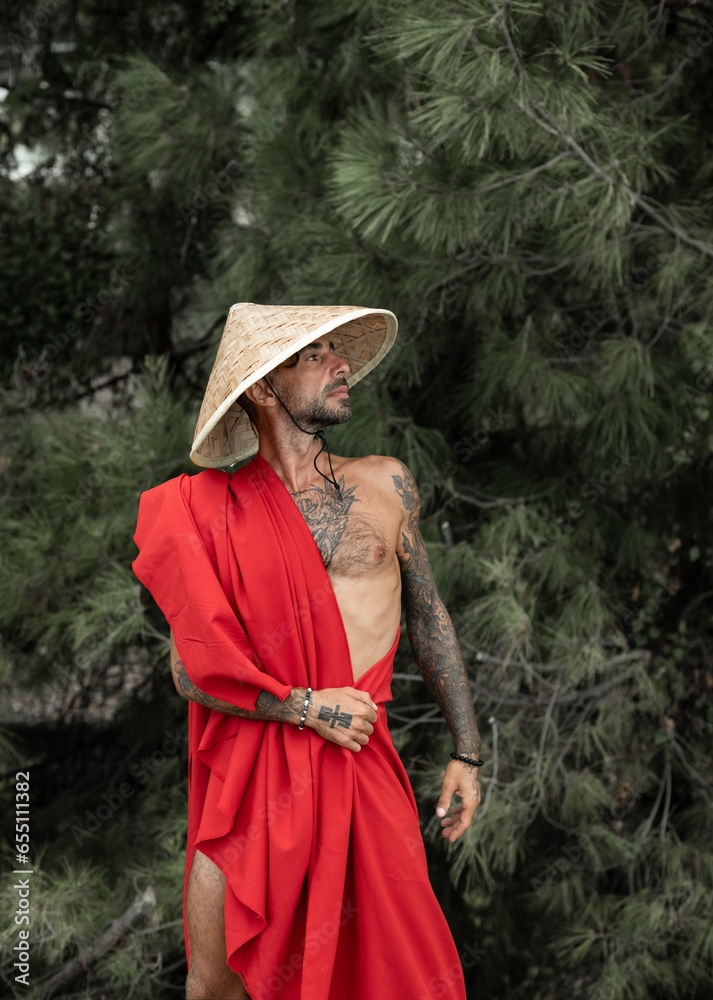 sexy male monk in a red cape and Asian hat in tattoos in nature Stock ...