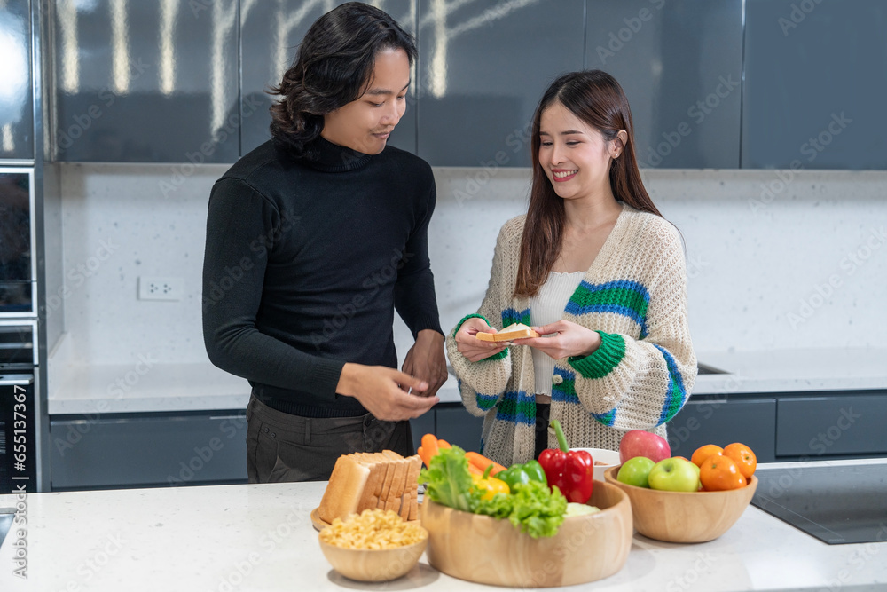 Husband and wife prepare breakfast in the kitchen, girlfriend holds ...