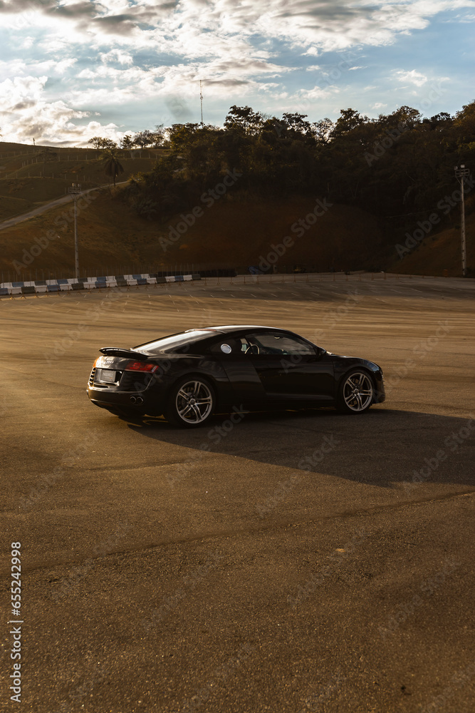 Black Audi R8 V8 Rear end view casting a shadow on the asphalt during ...