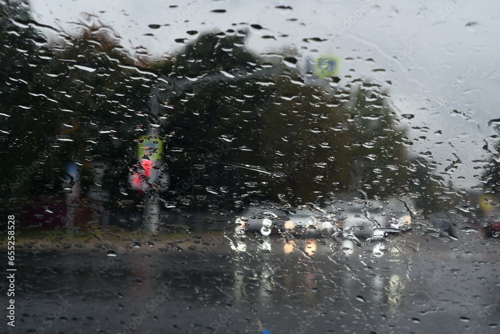View of an intersection with a traffic light and cars through a rain ...