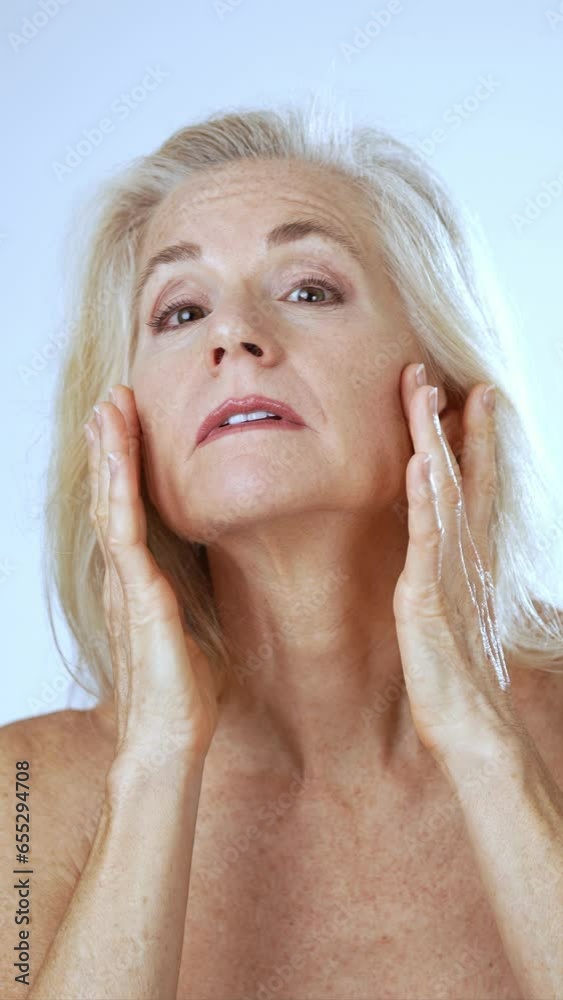 Vertical video portrait of mature woman touching face around eyes ...