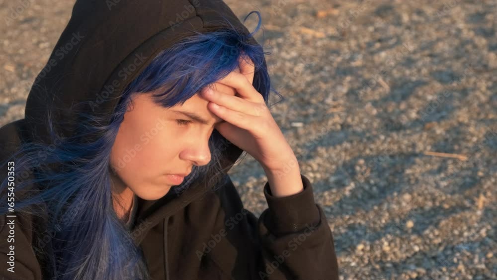 Angry blue haired girl on beach. An angry alone blue haired girl sits ...