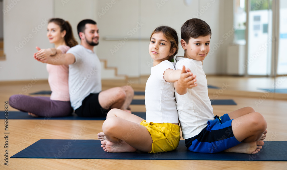 Tween girl with brother sitting on mat in modern yoga studio during ...