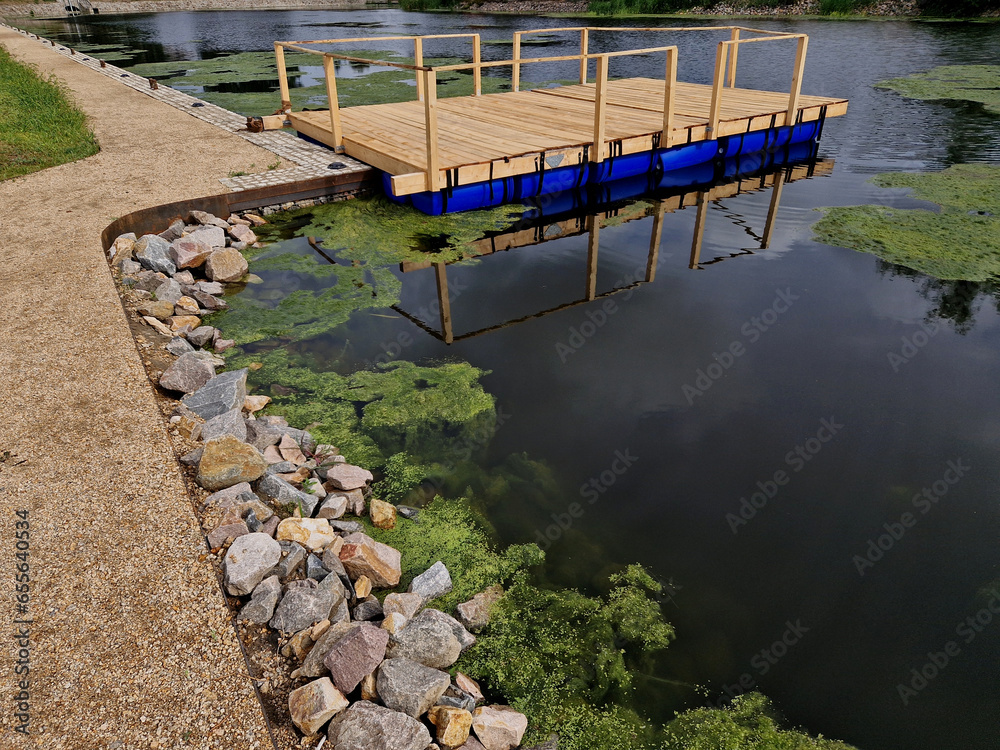 Pier for park visitors. two steps lead to it. planks terrace over water ...