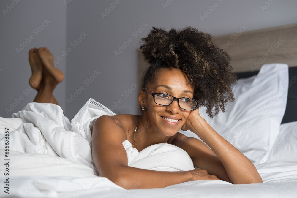 Portrait of a beautiful happy young black woman waking up in a ...