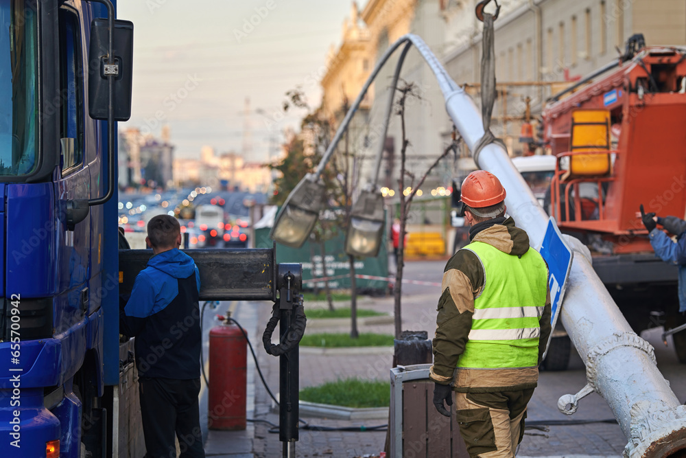 Replacement lamp columns. Crane lifting old street light pole. Street ...