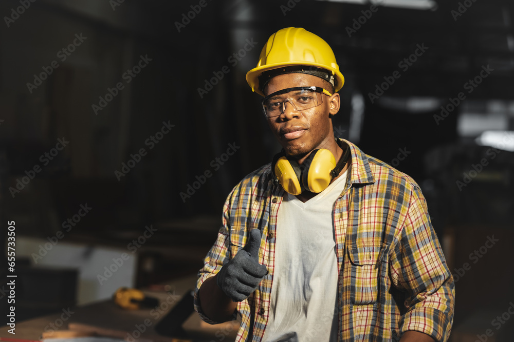 african black male worker in workshop with safety helmet and earmuff ...