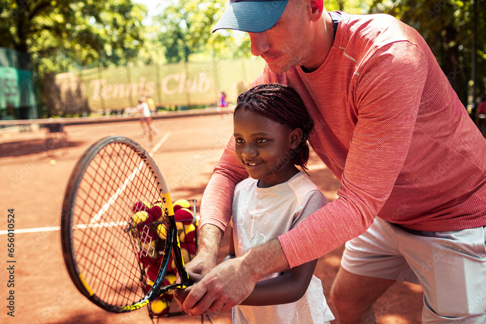 Tennis couch teaching a young girl correct racket positioning on a clay ...