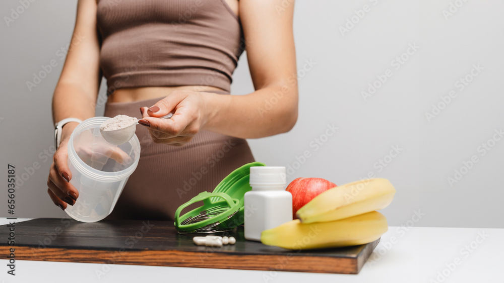 Athletic woman in sportswear with measuring spoon in her hand puts ...