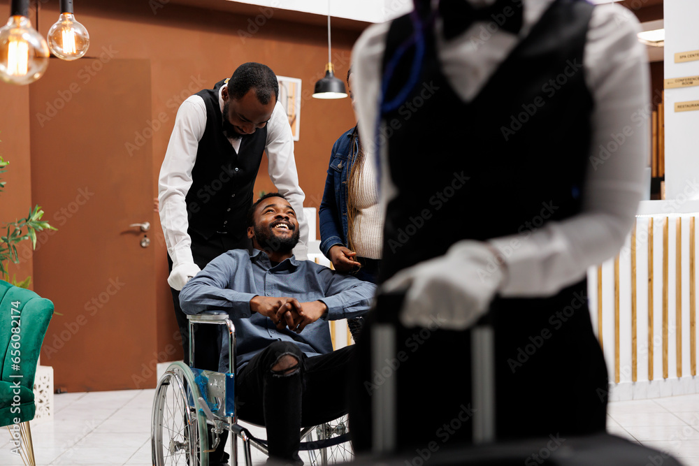 Wheelchair-friendly travel. Helpful hotel staff helping happy young ...