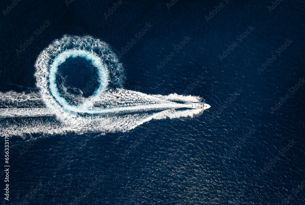 Aerial top view of a motor powerboat forming a circle of waves and ...